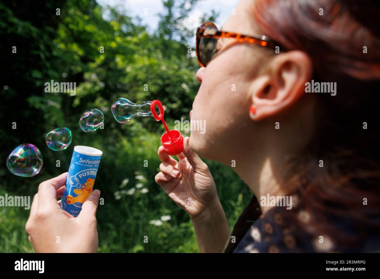 Stuttgart, Germany. 24th May, 2023. A woman blows soap bubbles with a ...
