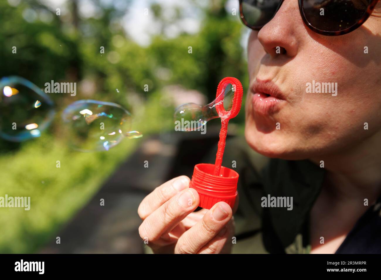 Stuttgart, Germany. 24th May, 2023. A woman blows soap bubbles with a ...