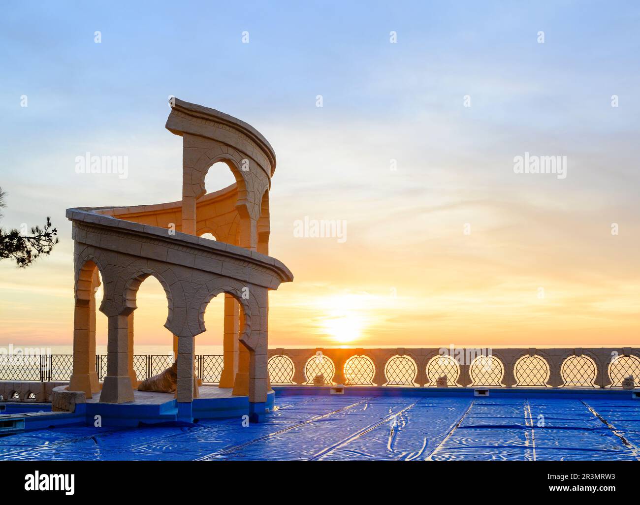 Spiral with stone columns next to a tree on the seashore at sunset ...