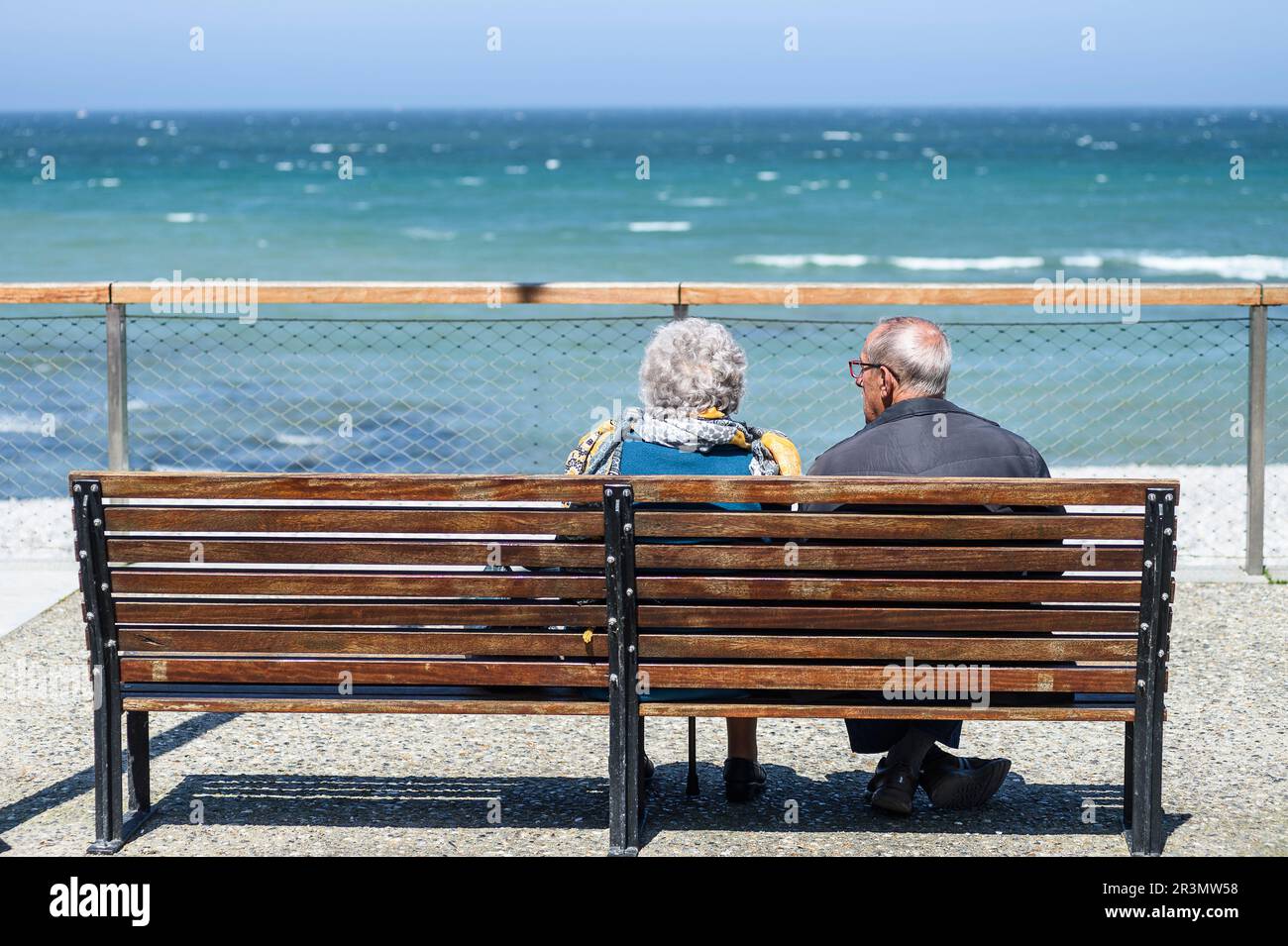 Couple in love on a bench sitting together looking to the horizon ...