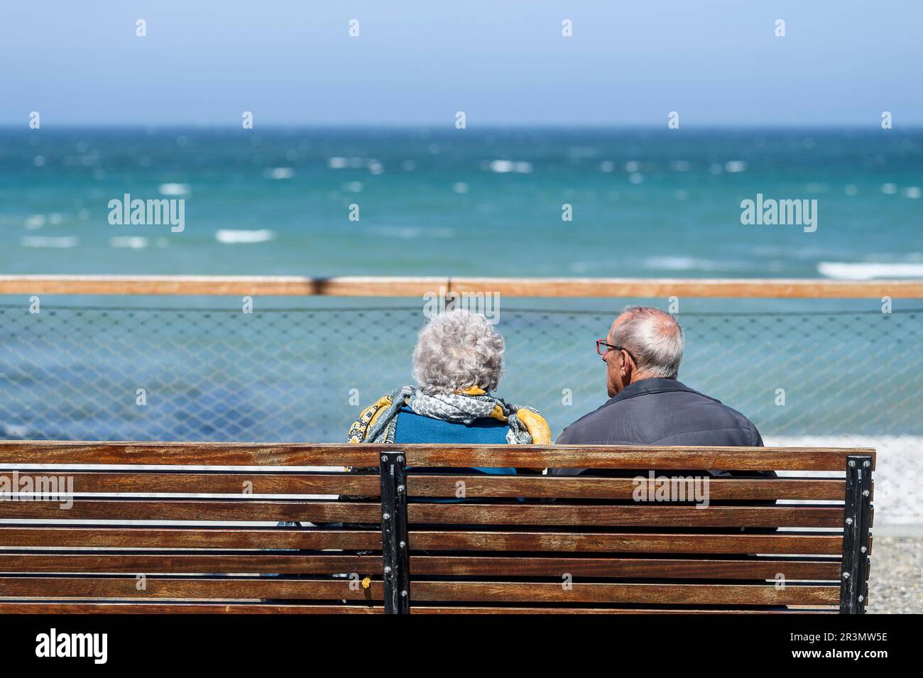 Couple in love on a bench sitting together looking to the horizon ...