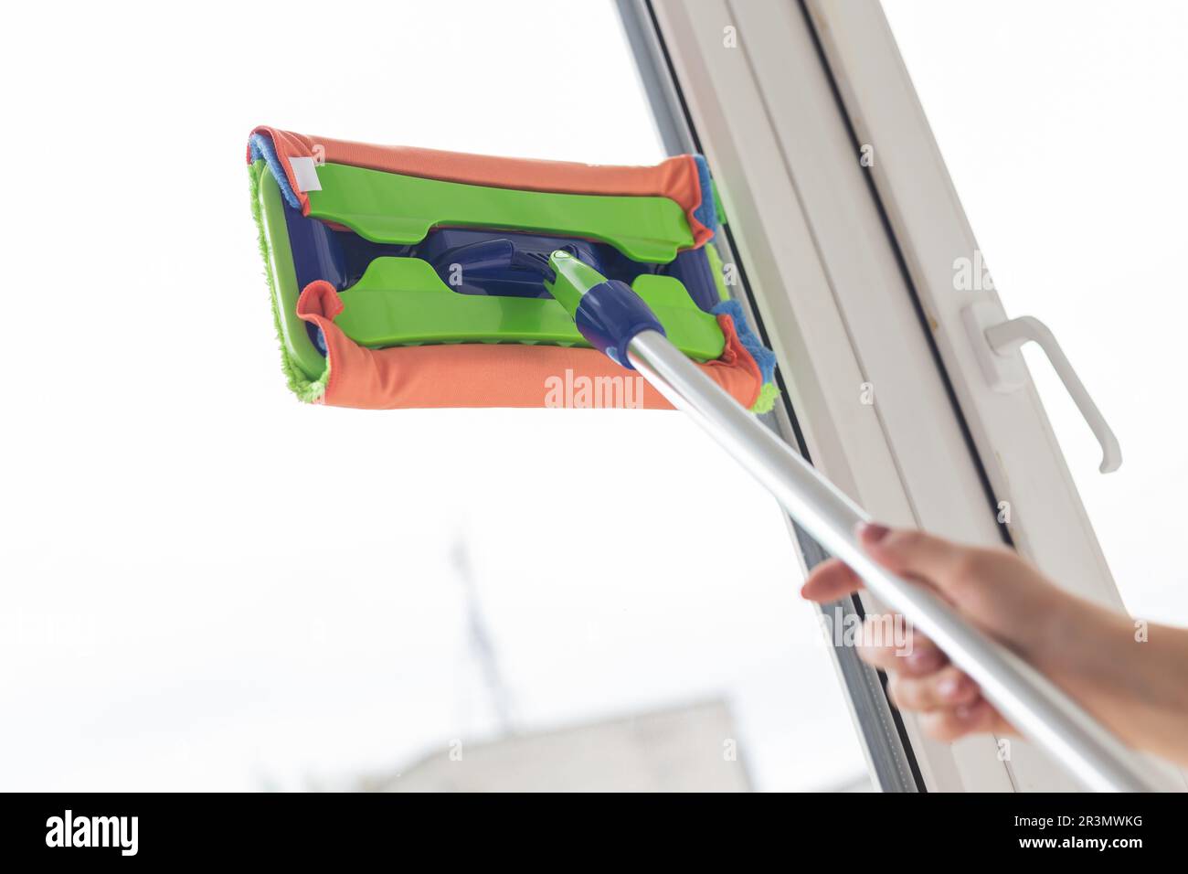 Happy woman cleaning window with sponge mop at home - housework and ...