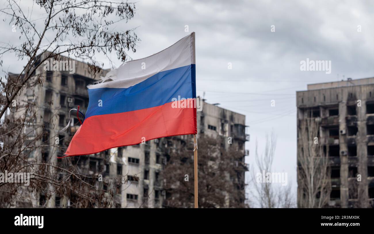 Tricolor flag of Russia against the background of destroyed and burnt ...