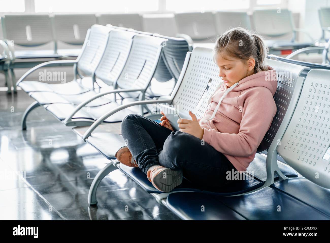 Kid, teen girl waiting for plane flight in departure hall. Sitting on ...