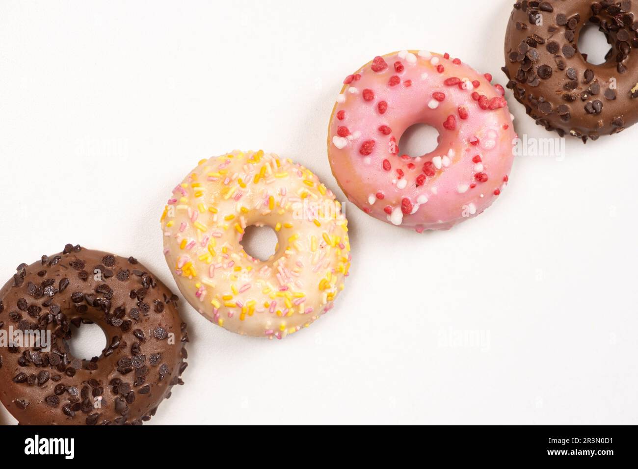 Four donuts in a row - white, pink and chocolate on a white background ...