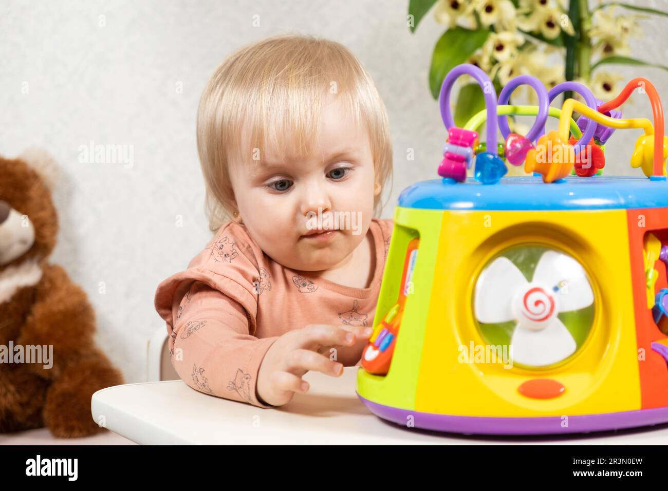 A one-and-a-half-year-old girl plays with a musical glowing toy ...