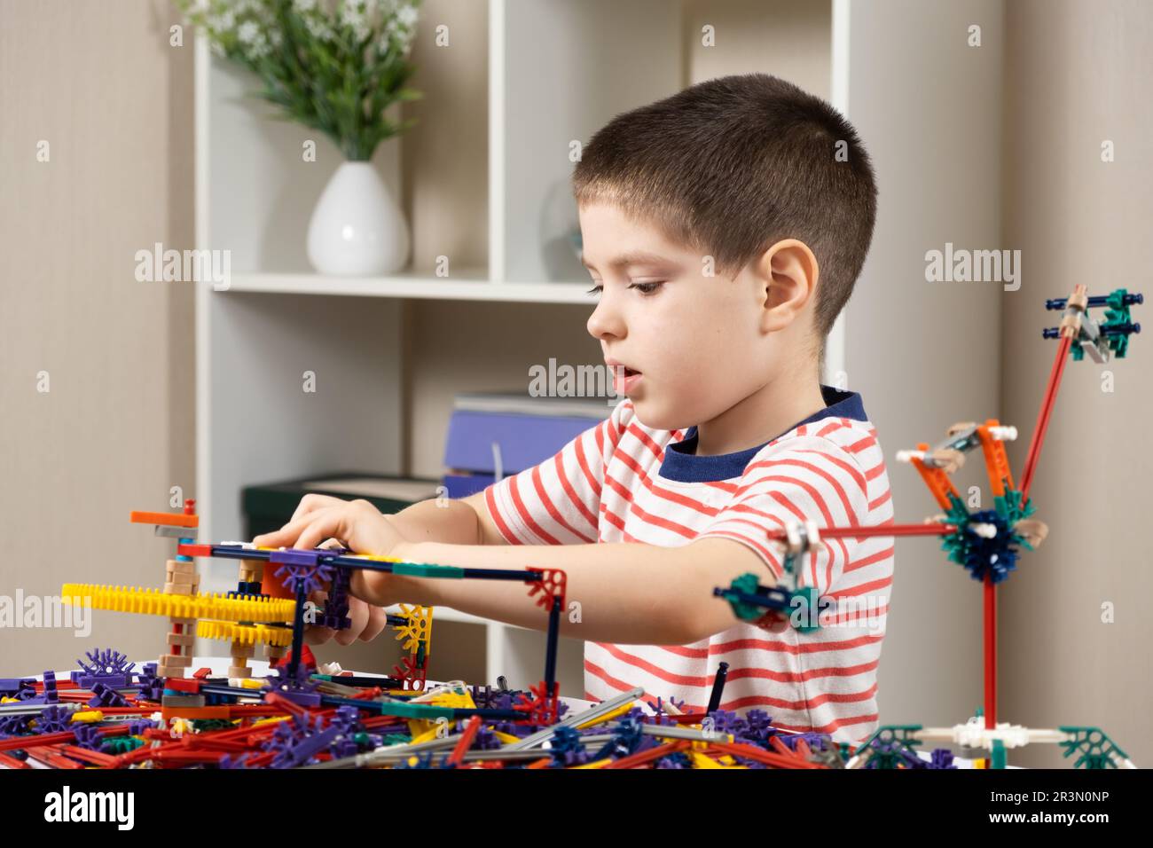 A little boy plays with a constructor, creating figures from gears and ...