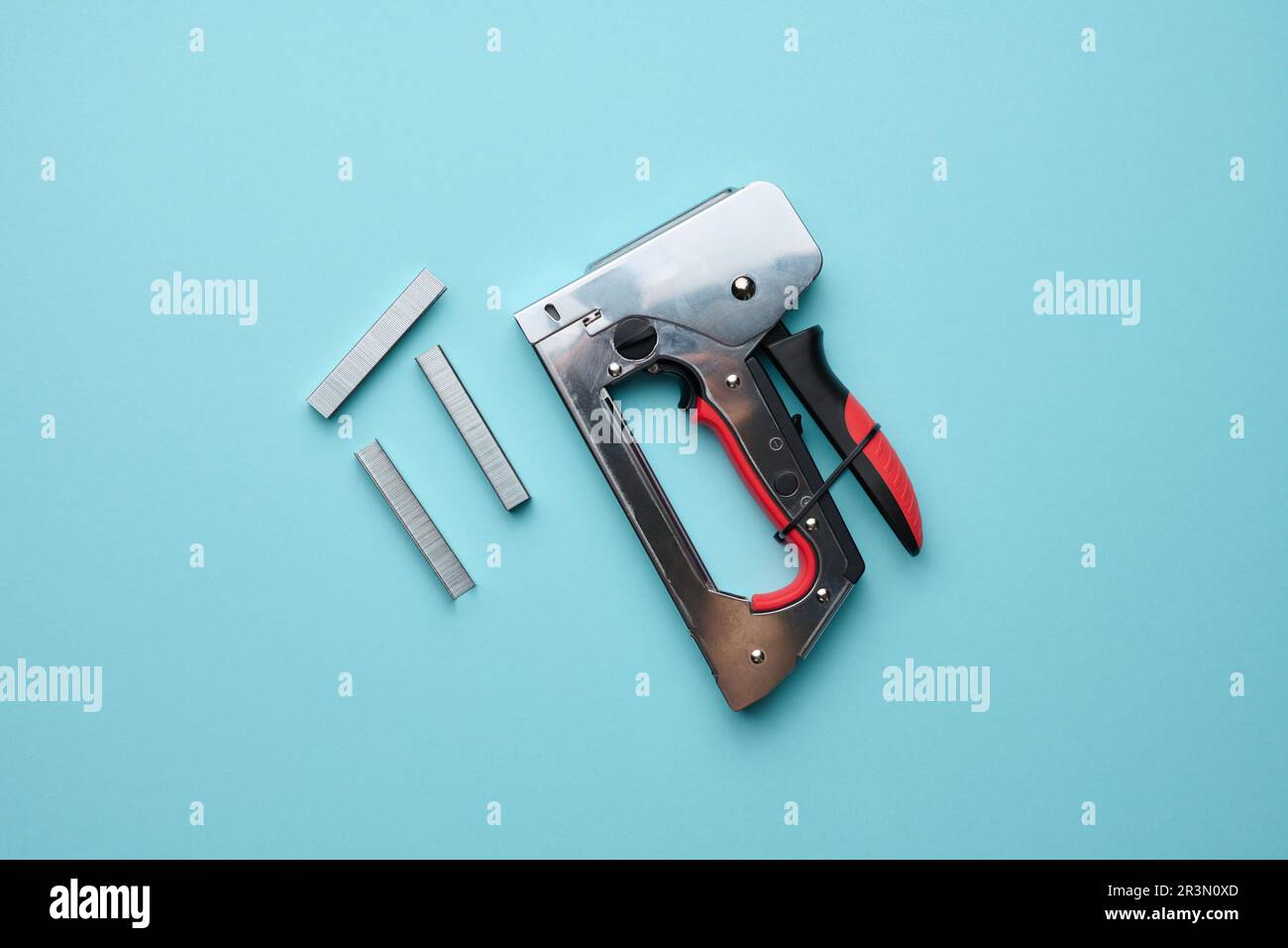 Household manual stapler and staples on a blue background, top view ...