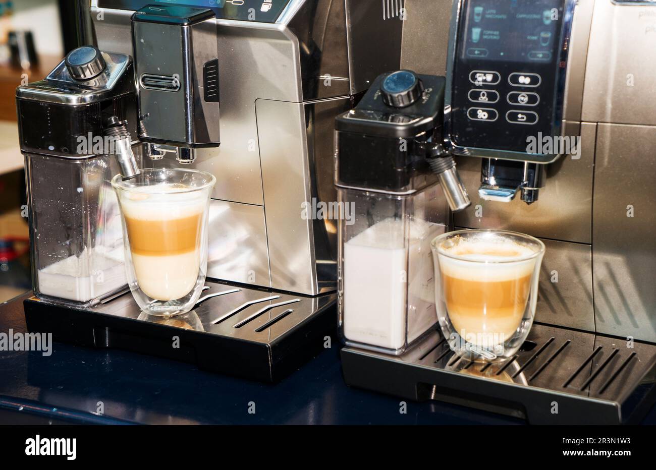 A coffee machine pours espresso into a glass cup with milk. Cappuccino ...