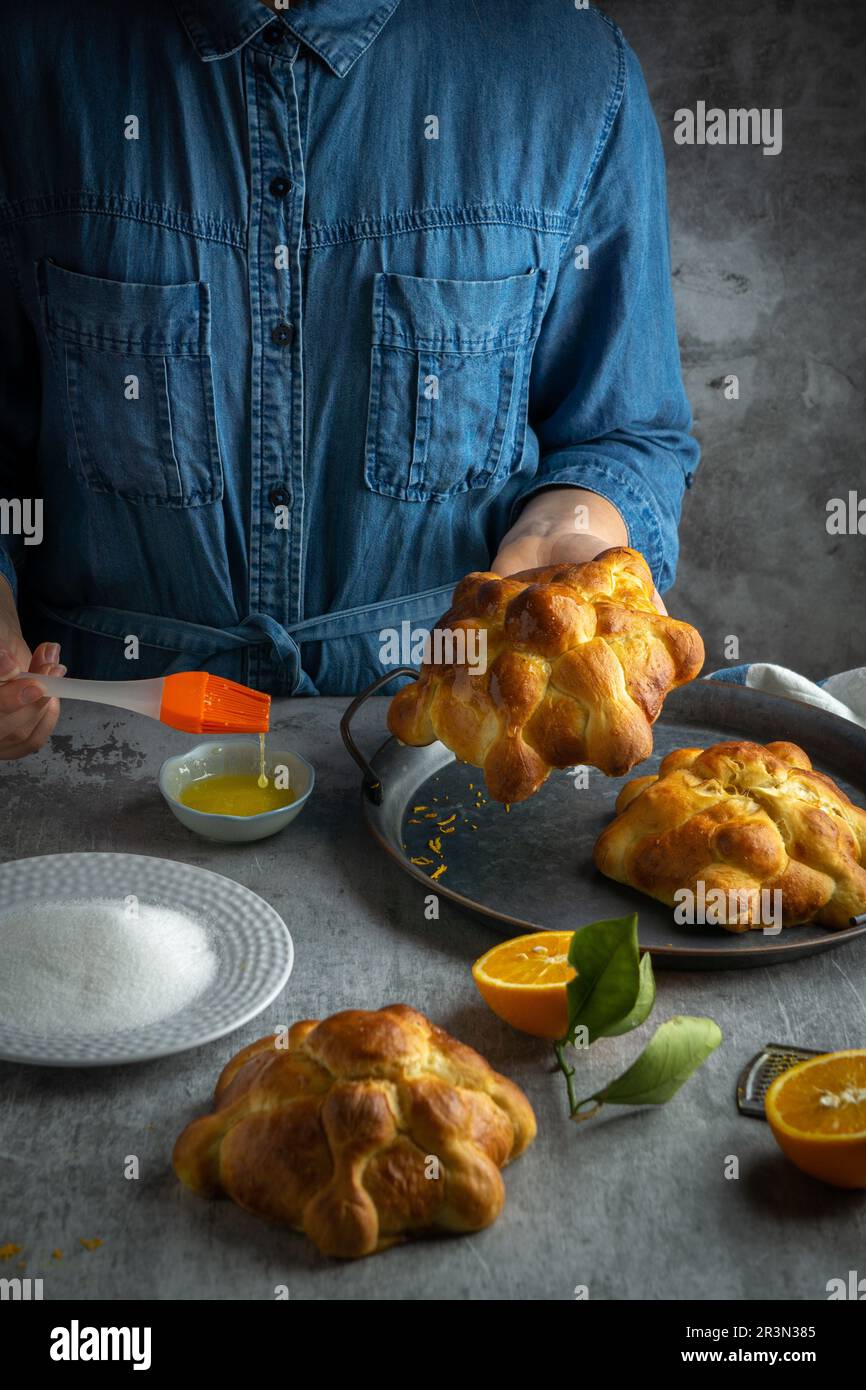 Woman preparing Pan de muertos bread of the dead for Mexican day of the ...