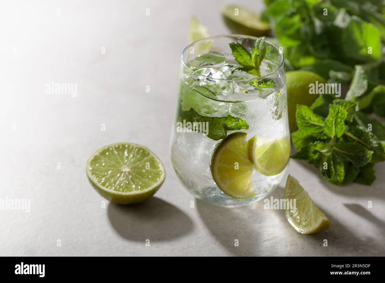 Mojito with ice, lime, and mint on a white stone table. Cold refreshing ...