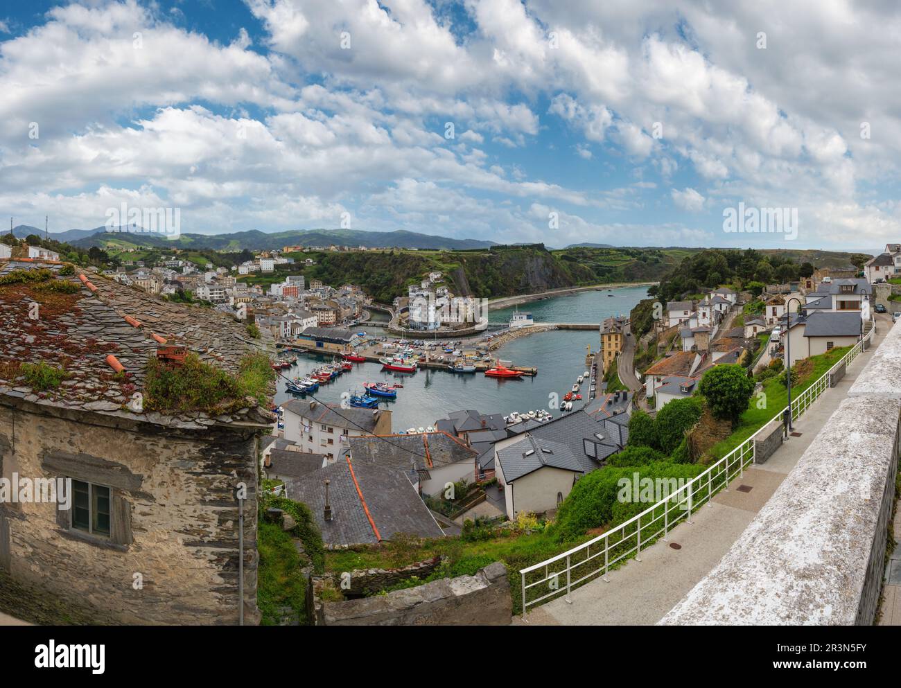 Evening Luarca cityscape (top view) with colorful boats in fishing port ...