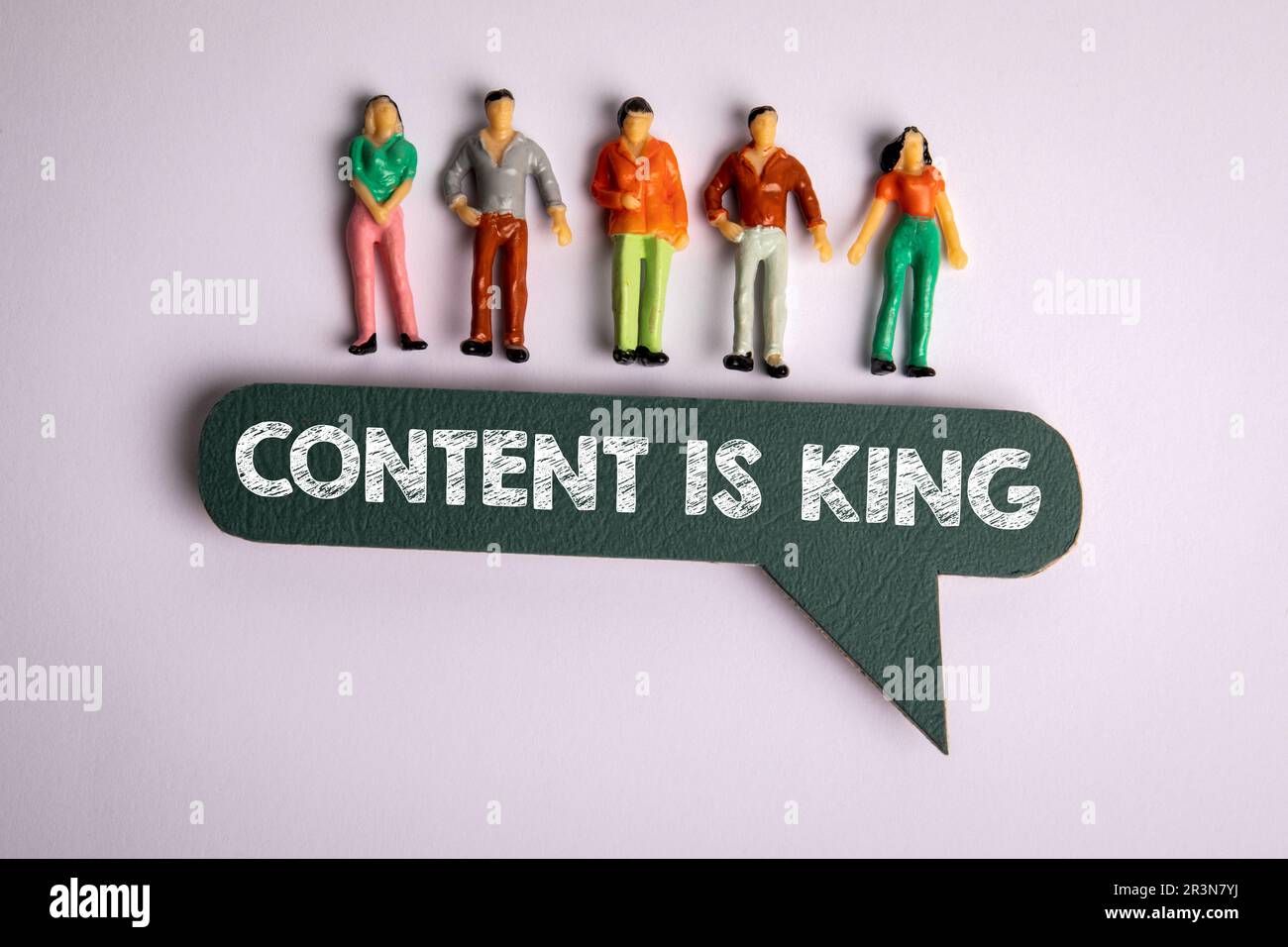 CONTENT IS KING CONCEPT. Miniature human figures and speech bubble on a ...