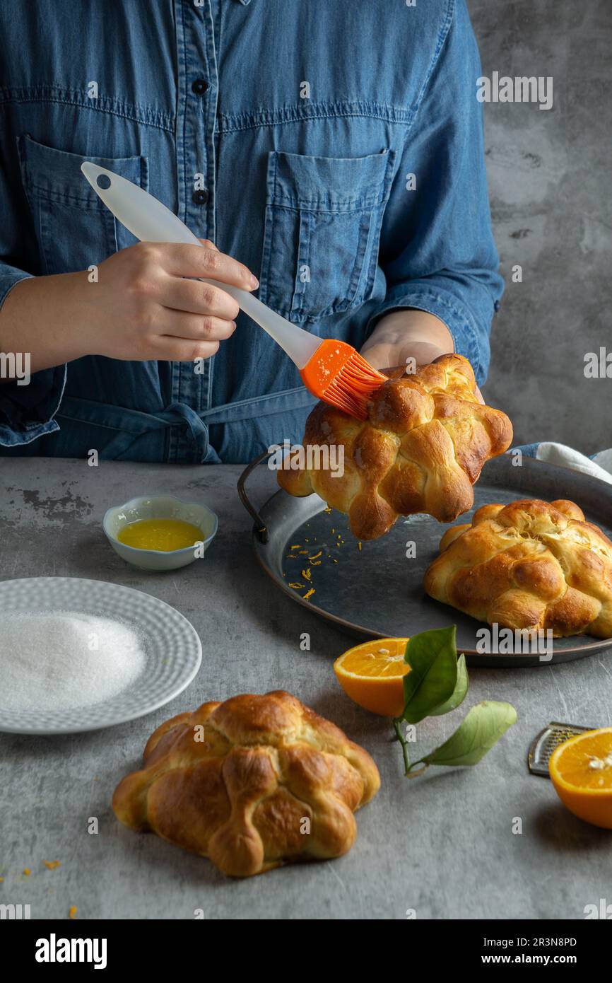 Woman preparing Pan de muertos bread of the dead for Mexican day of the ...