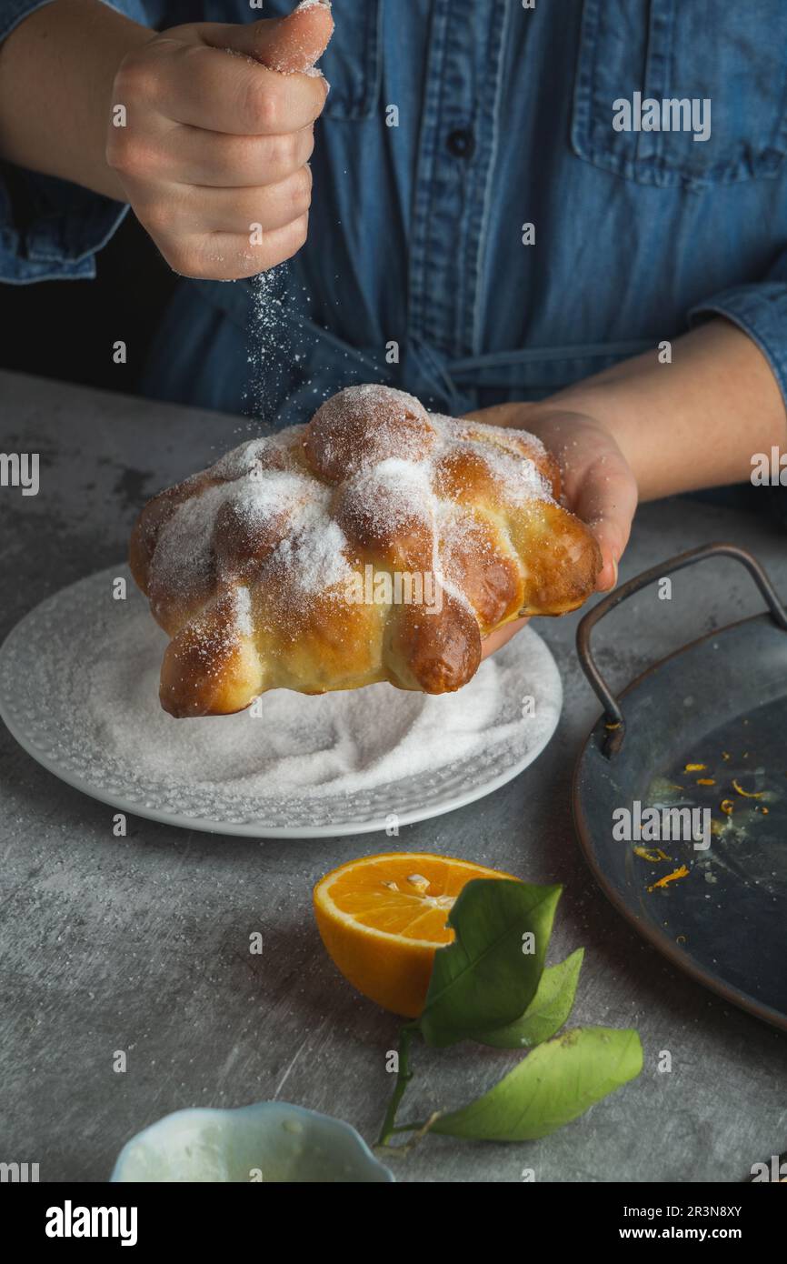 Woman preparing Pan de muertos bread of the dead for Mexican day of the ...