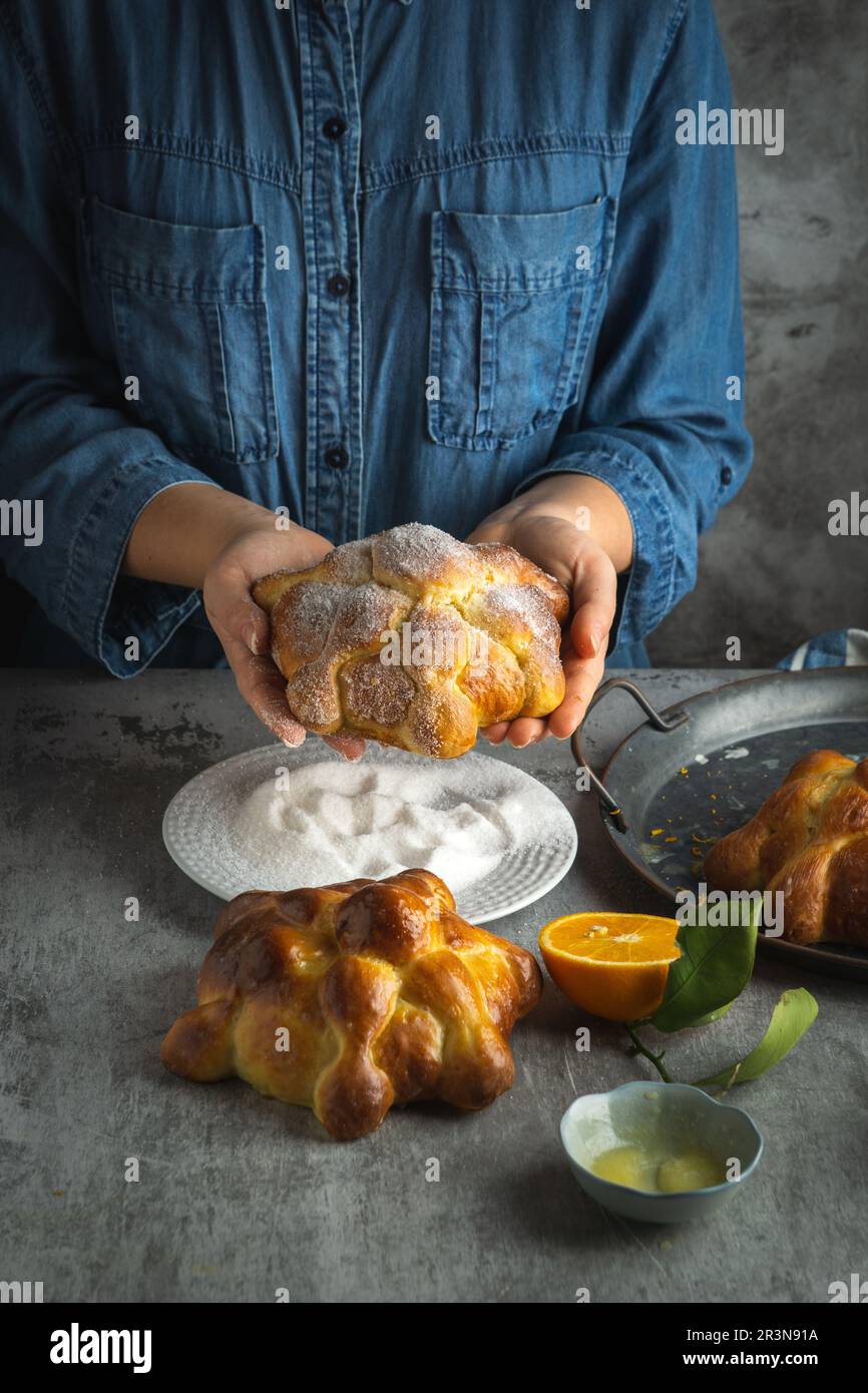 Woman preparing Pan de muertos bread of the dead for Mexican day of the ...