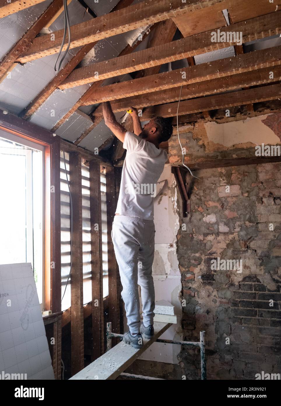 Construction worker installing loft insulation boards into an attic of ...