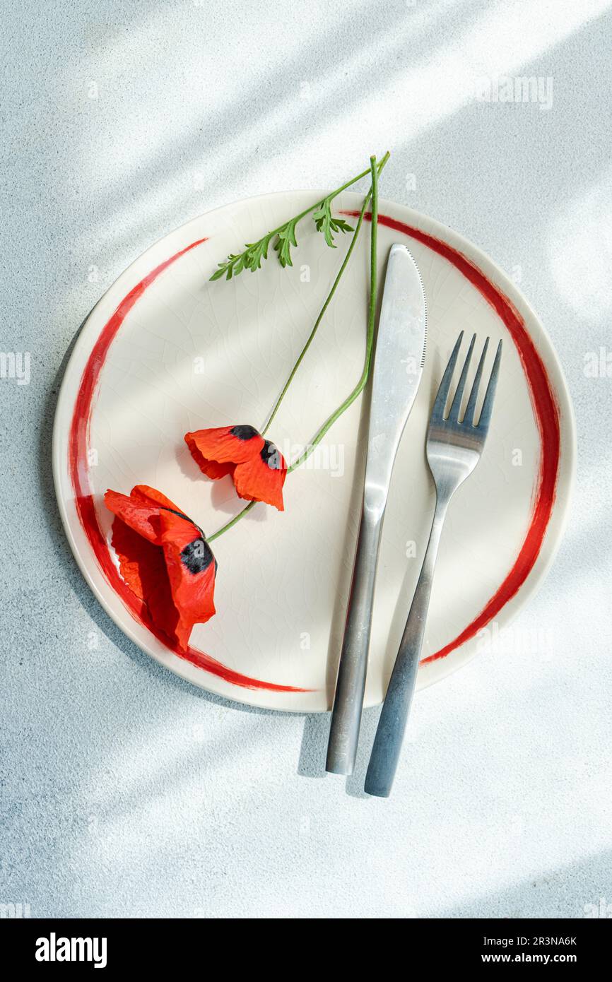 From above summer table with red poppy flowers on a white plate with ...