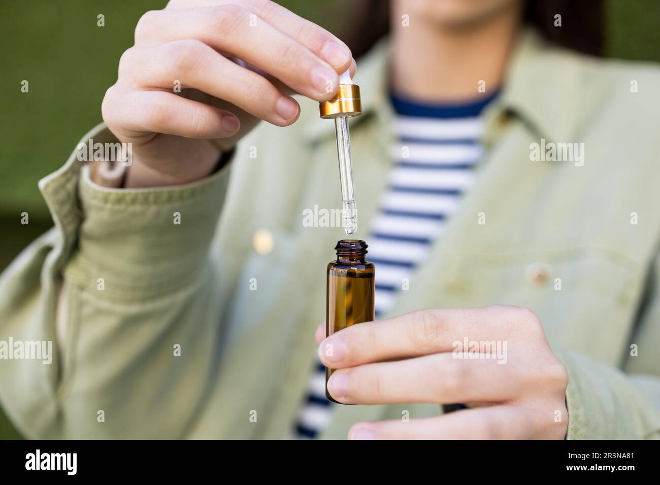 Anonymous female in casual clothes dripping liquid oil from tube into ...