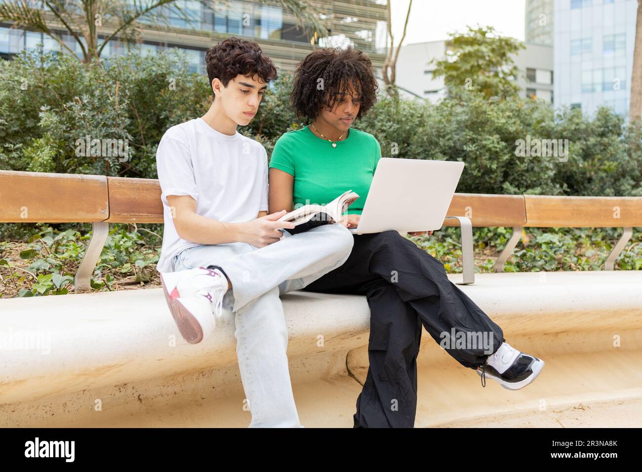 Concentrated young students sitting together on cement border with legs ...
