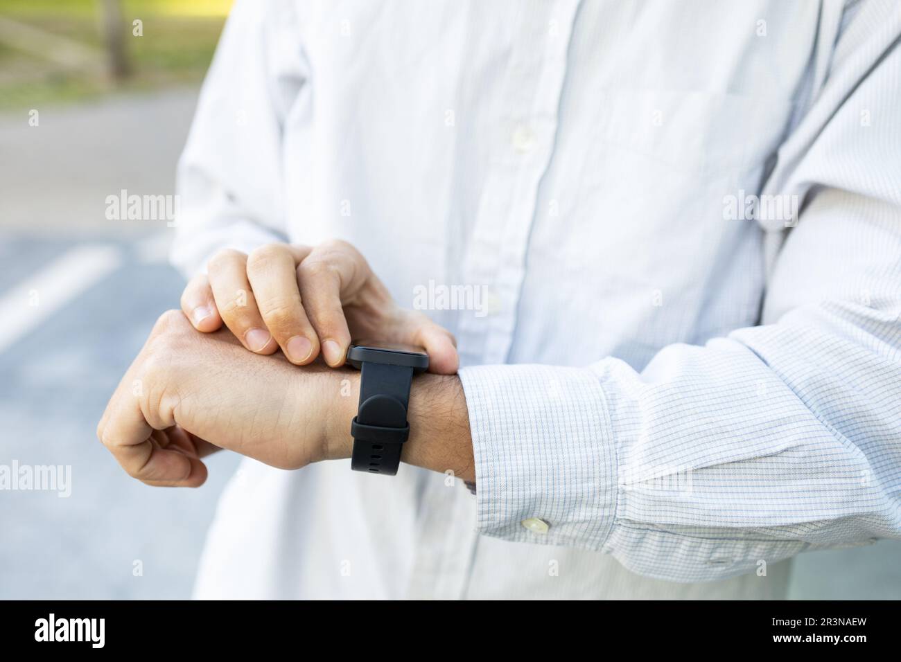 Crop unrecognizable male in white shirt with smart watch standing in ...