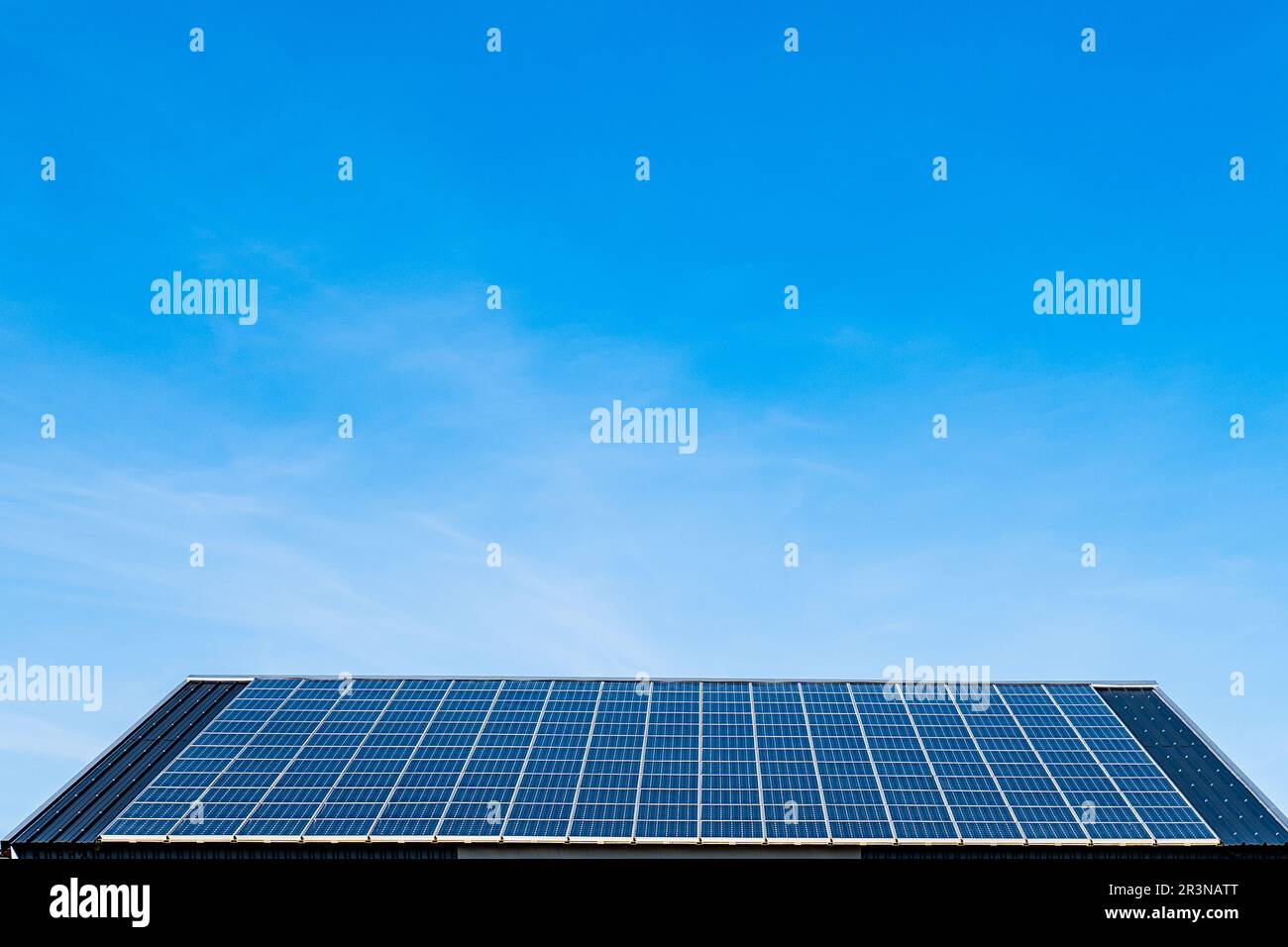 Multiple solar panels placed in pattern on top of inclined roof of ...