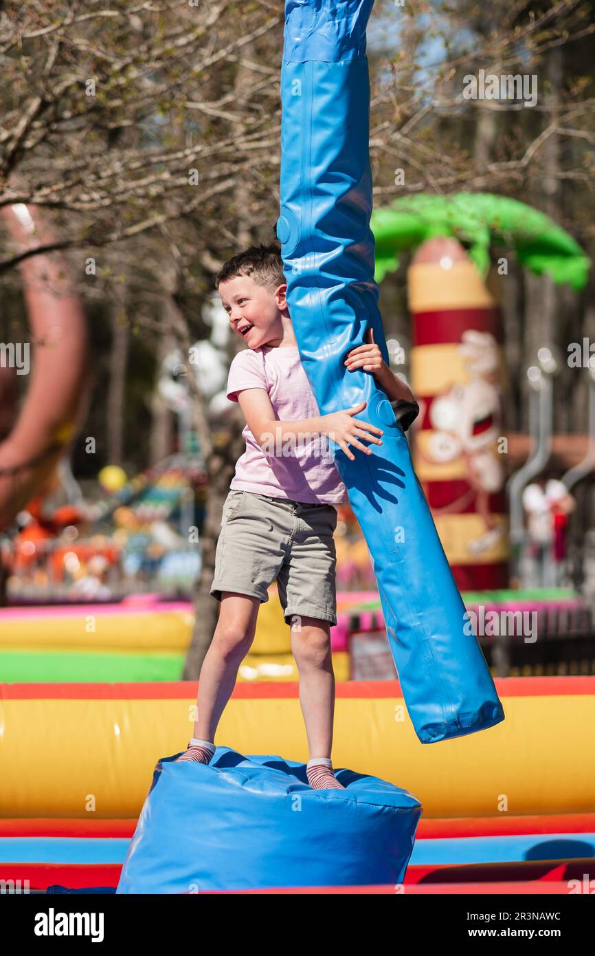 Laughing cute preteen boy standing on rubber bag and holding big ...