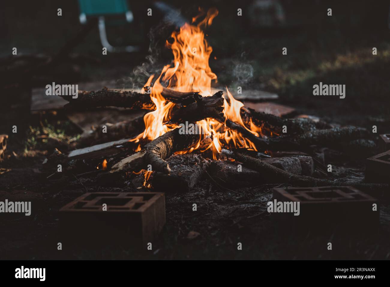 Bonfire with orange flames of wood burning with bricks around it during ...