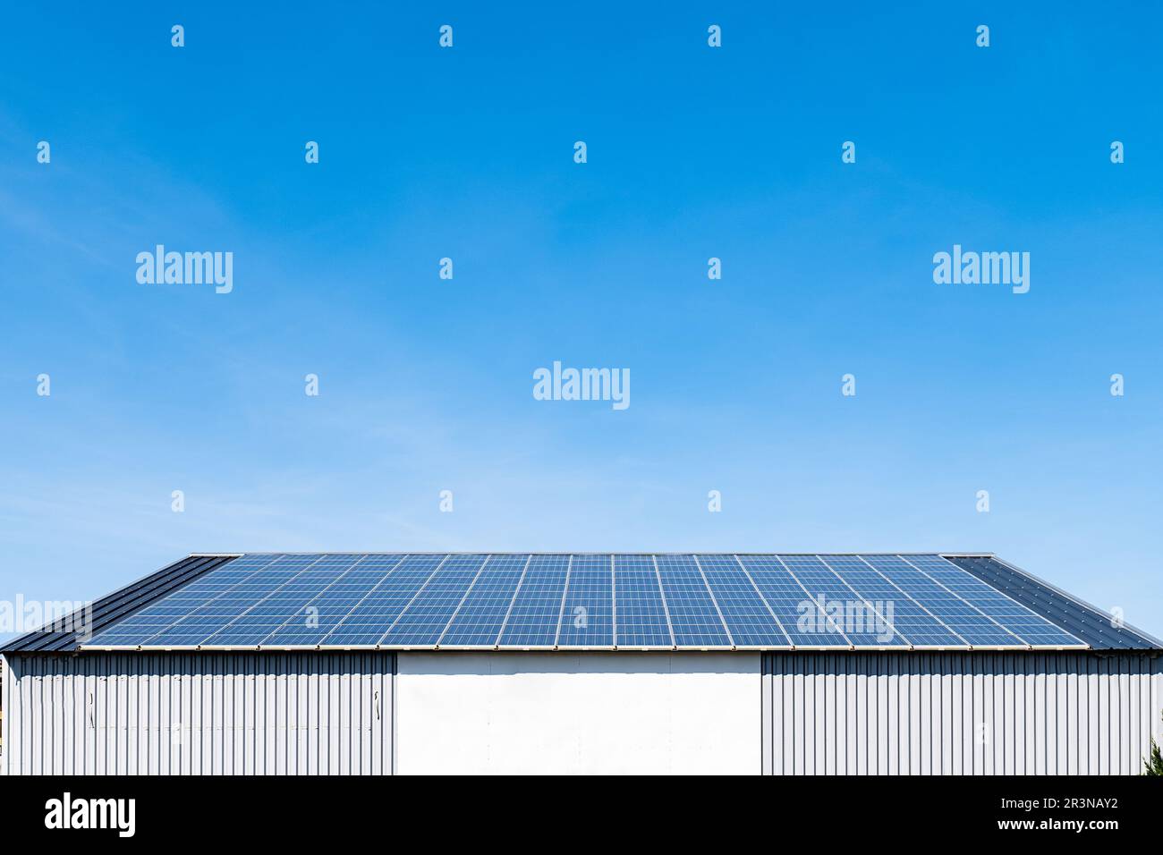 Multiple solar panels placed in pattern on top of inclined roof of ...