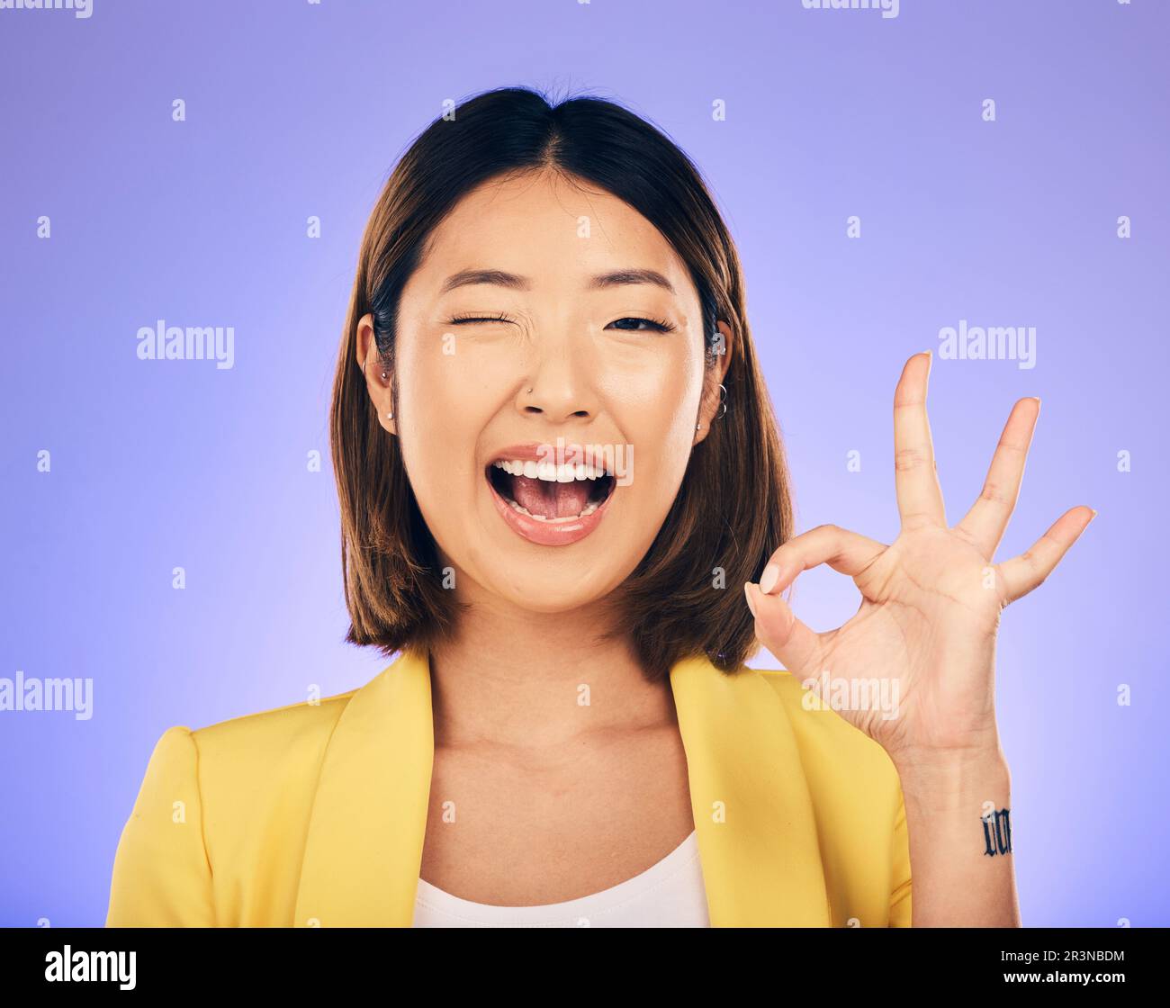 Portrait, smile and Asian woman with ok sign, wink and emoji against a ...