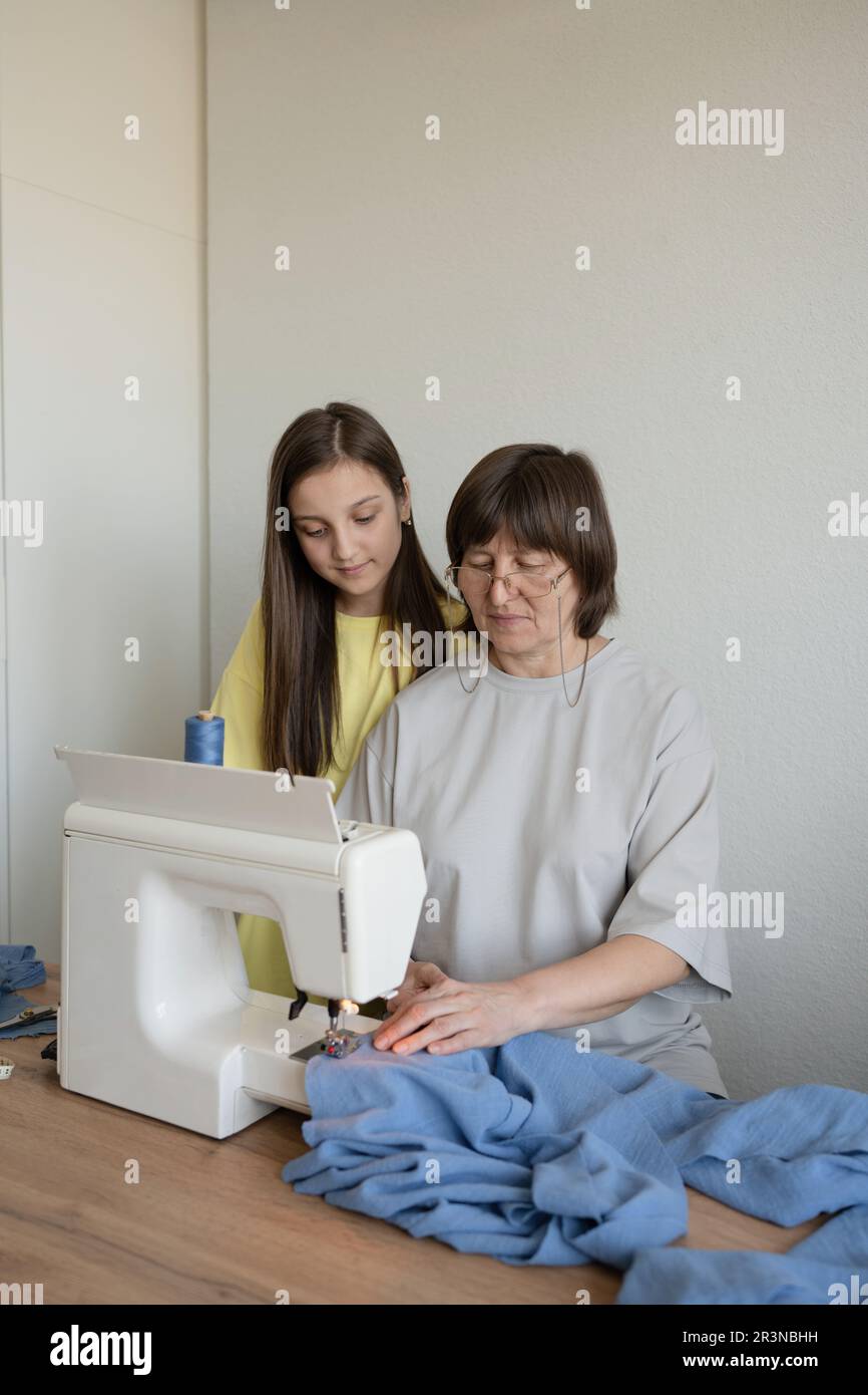 A quiet seamstress and a girl together near a sewing machine during ...