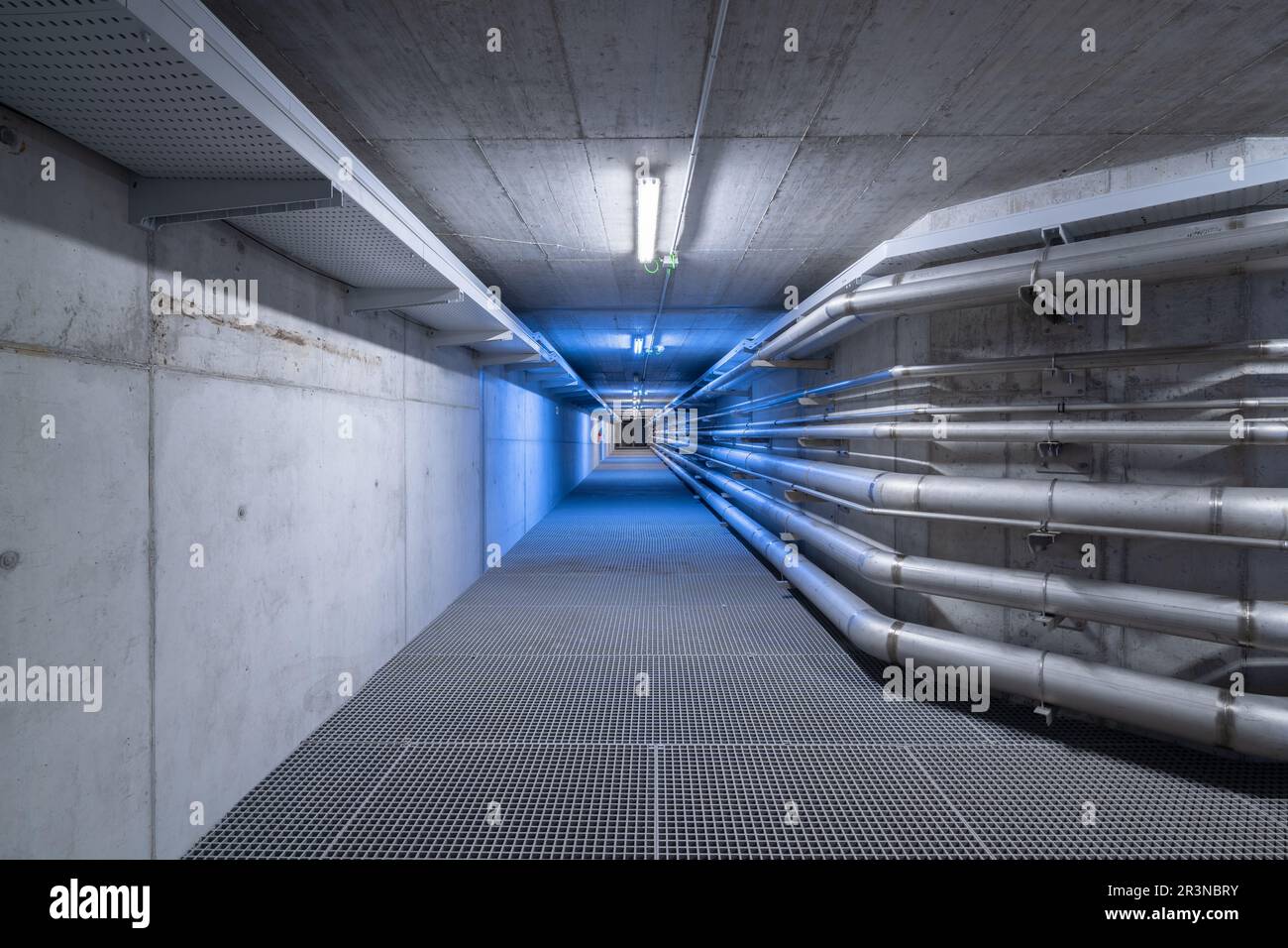 Long empty underground corridor with drainage system and metal ...