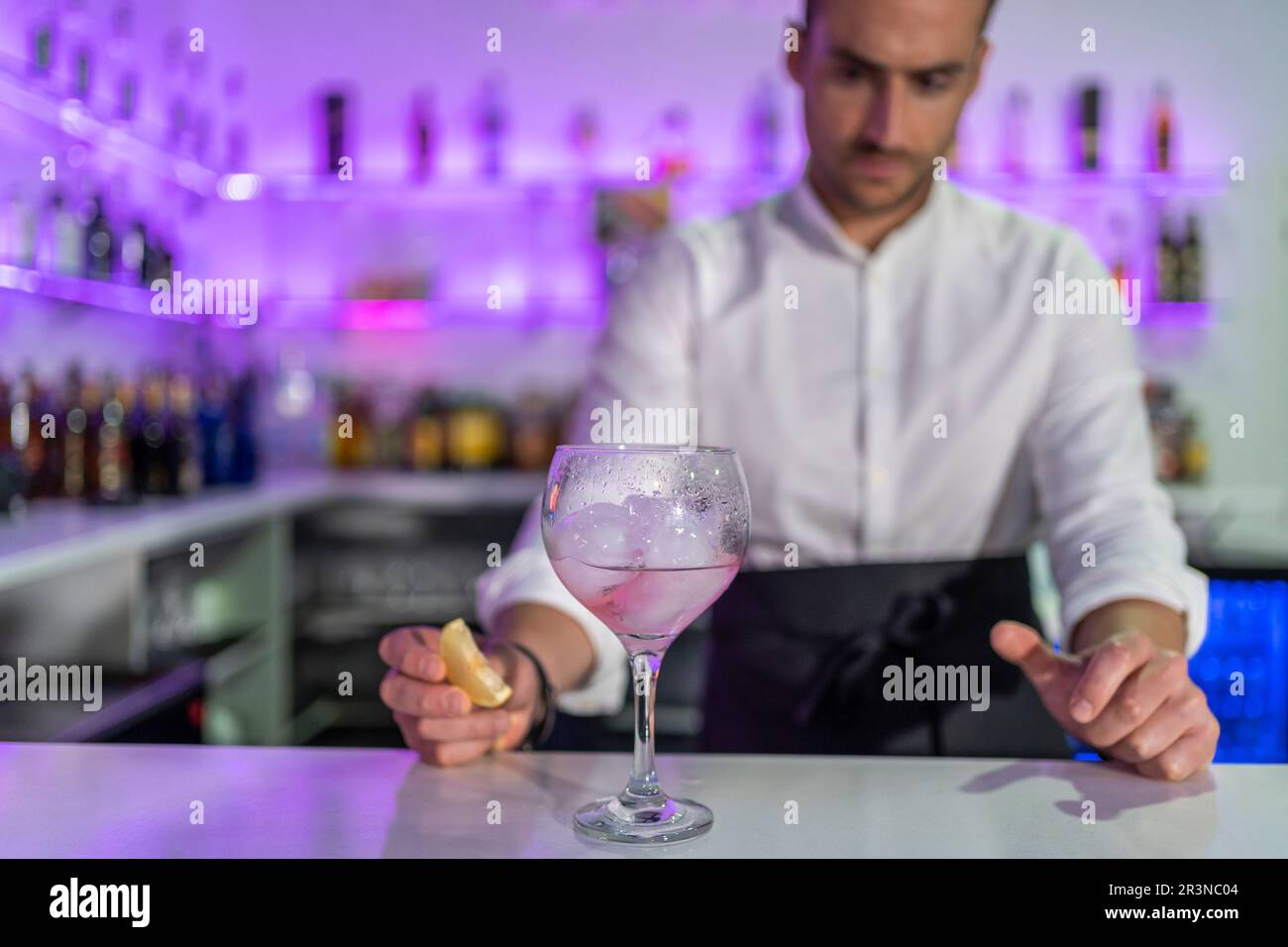 Unrecognizable male bartender with slice of orange in hand looking down ...