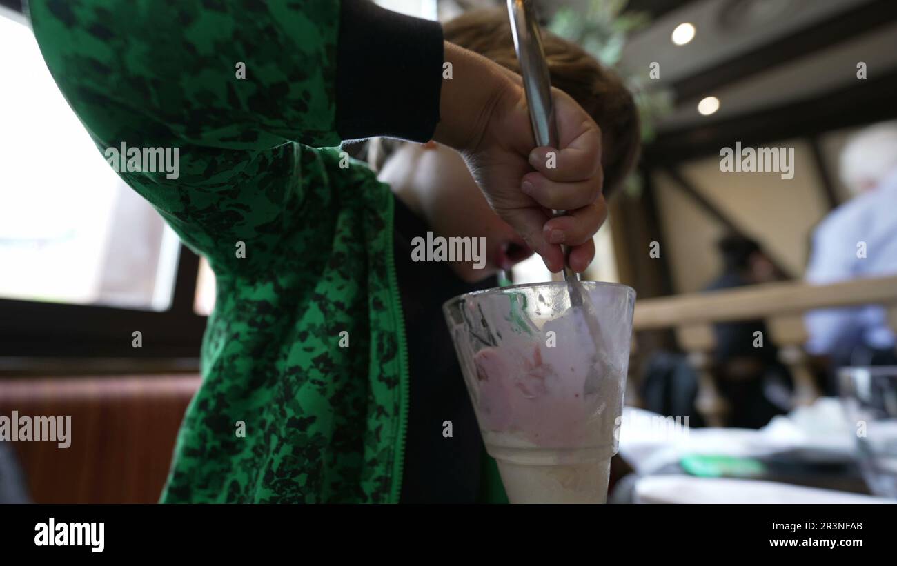Hungry child eating ice cream dessert at restaurant after meal Stock ...