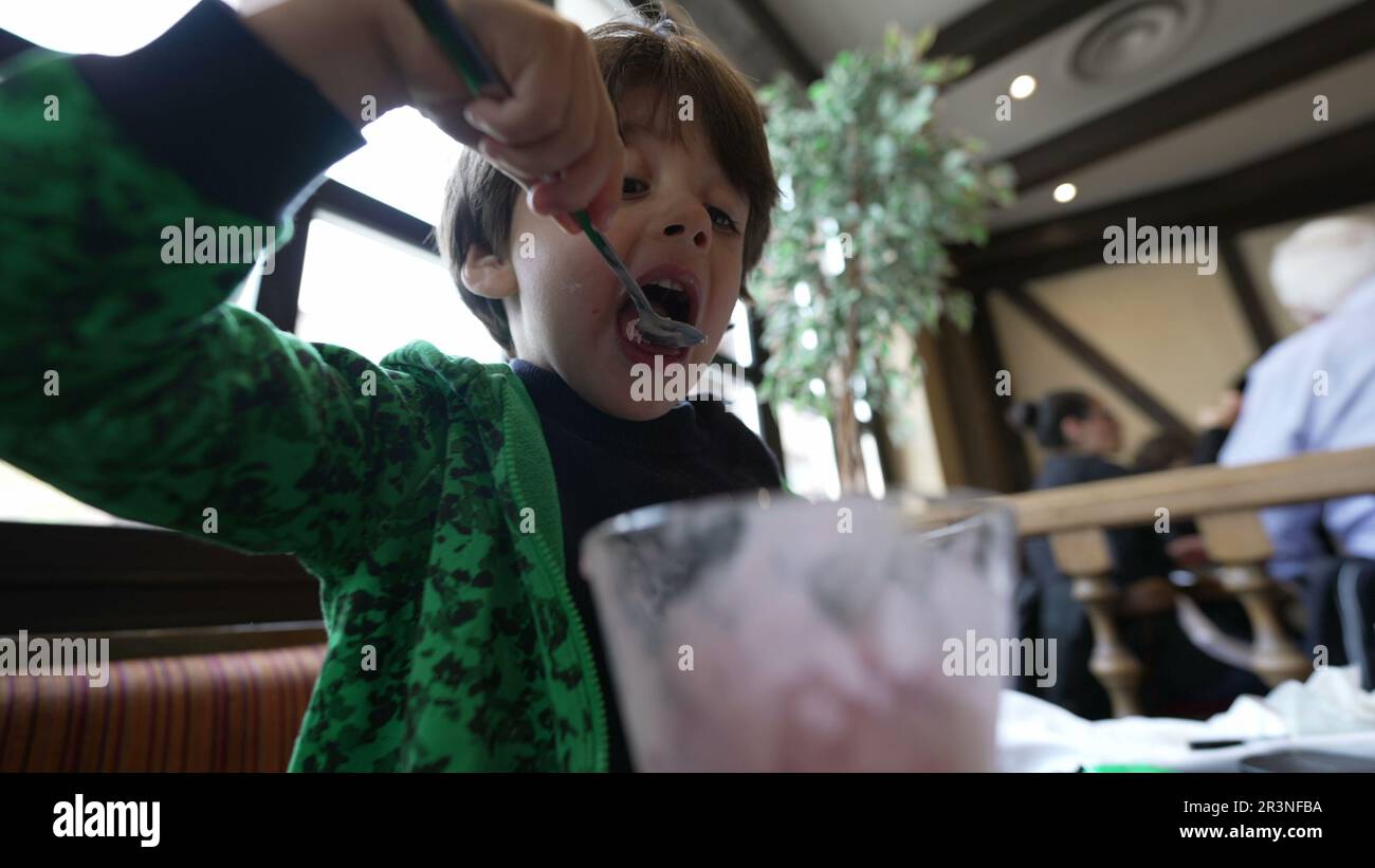 Hungry child eating ice cream dessert at restaurant after meal Stock ...