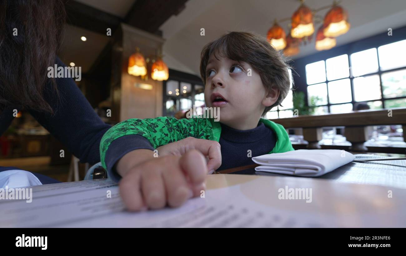 Little boy reading restaurant menu. Child sititng at table choosing ...