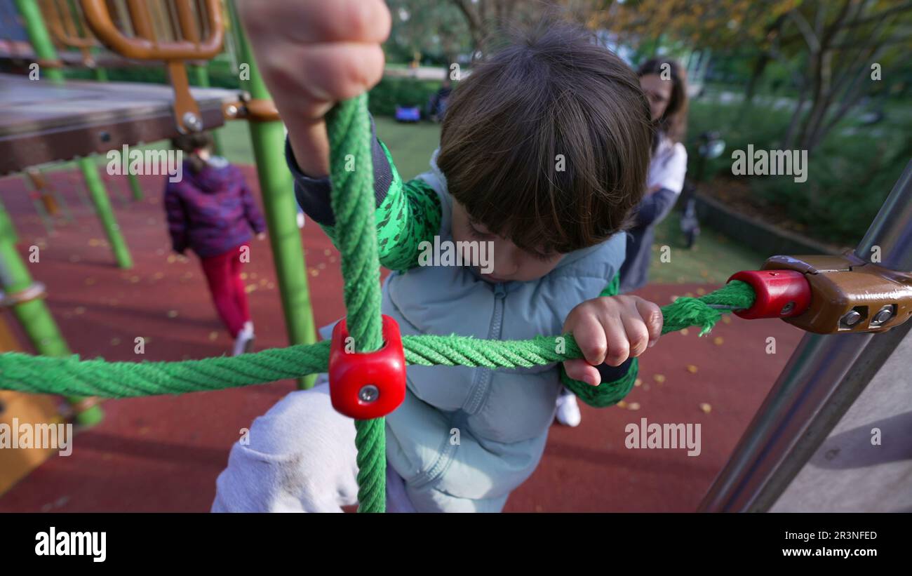 Active child climbing rope at playground outdoors. One happy male ...