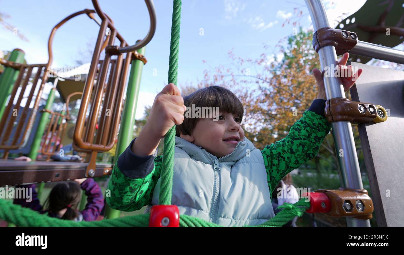 Active child climbing rope at playground outdoors. One happy male ...