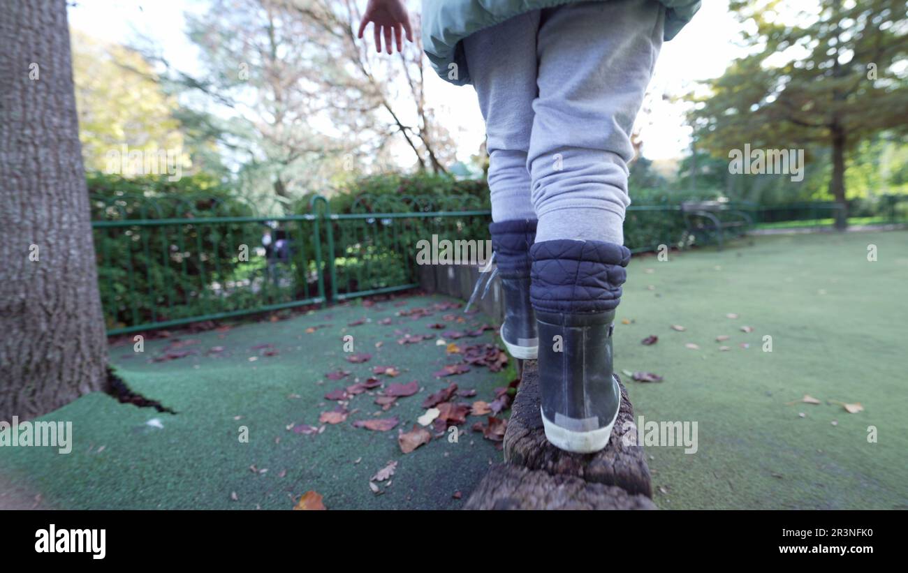 Child closeup feet wearing boots training balance at playground wooden ...