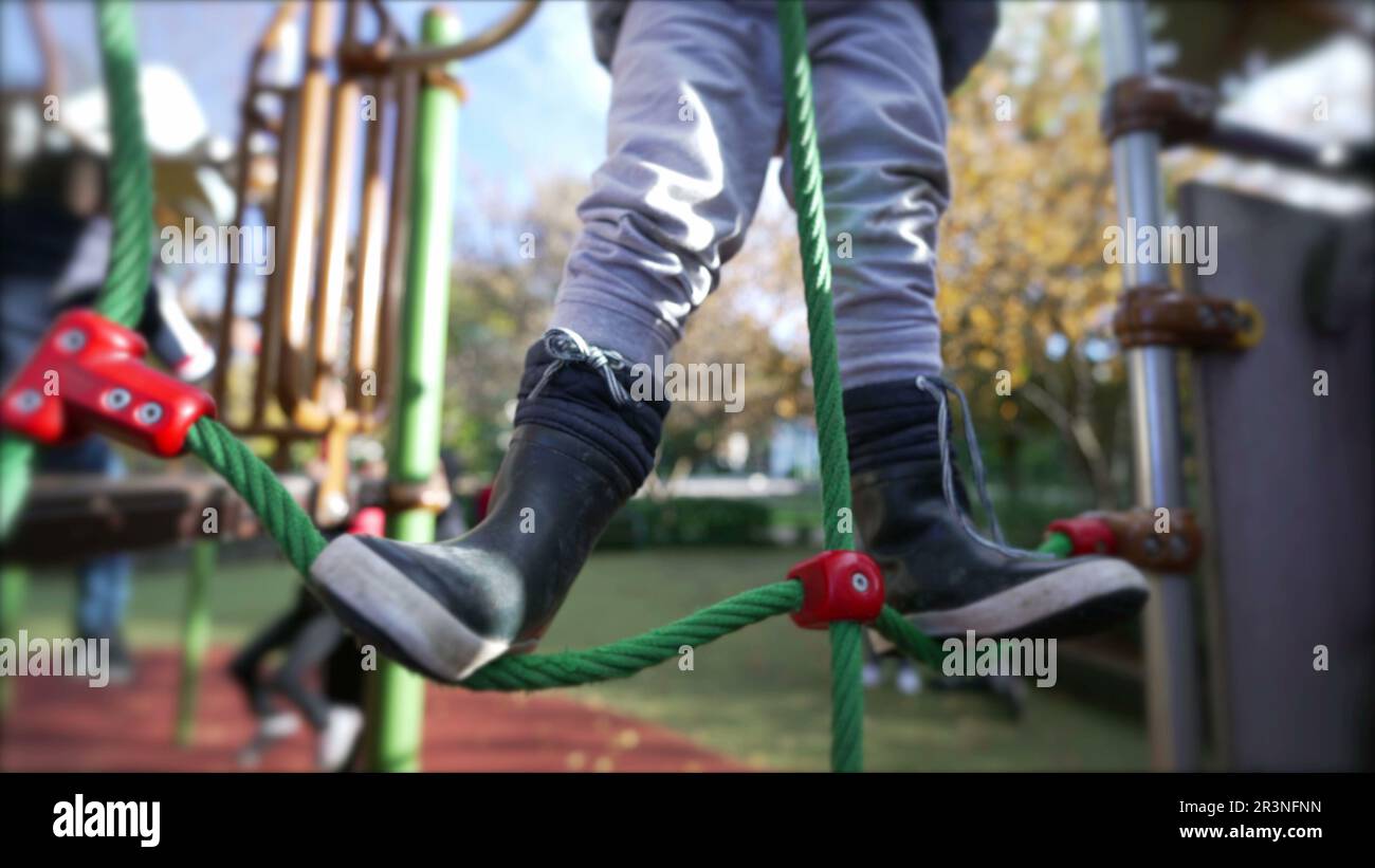 Closeup Child feet wearing boots holding into rope at playground ...