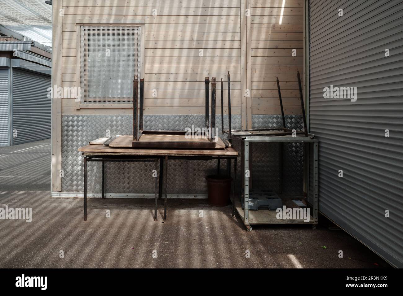 Exterior view in front of closed storefront, stack of stall tables, and ...