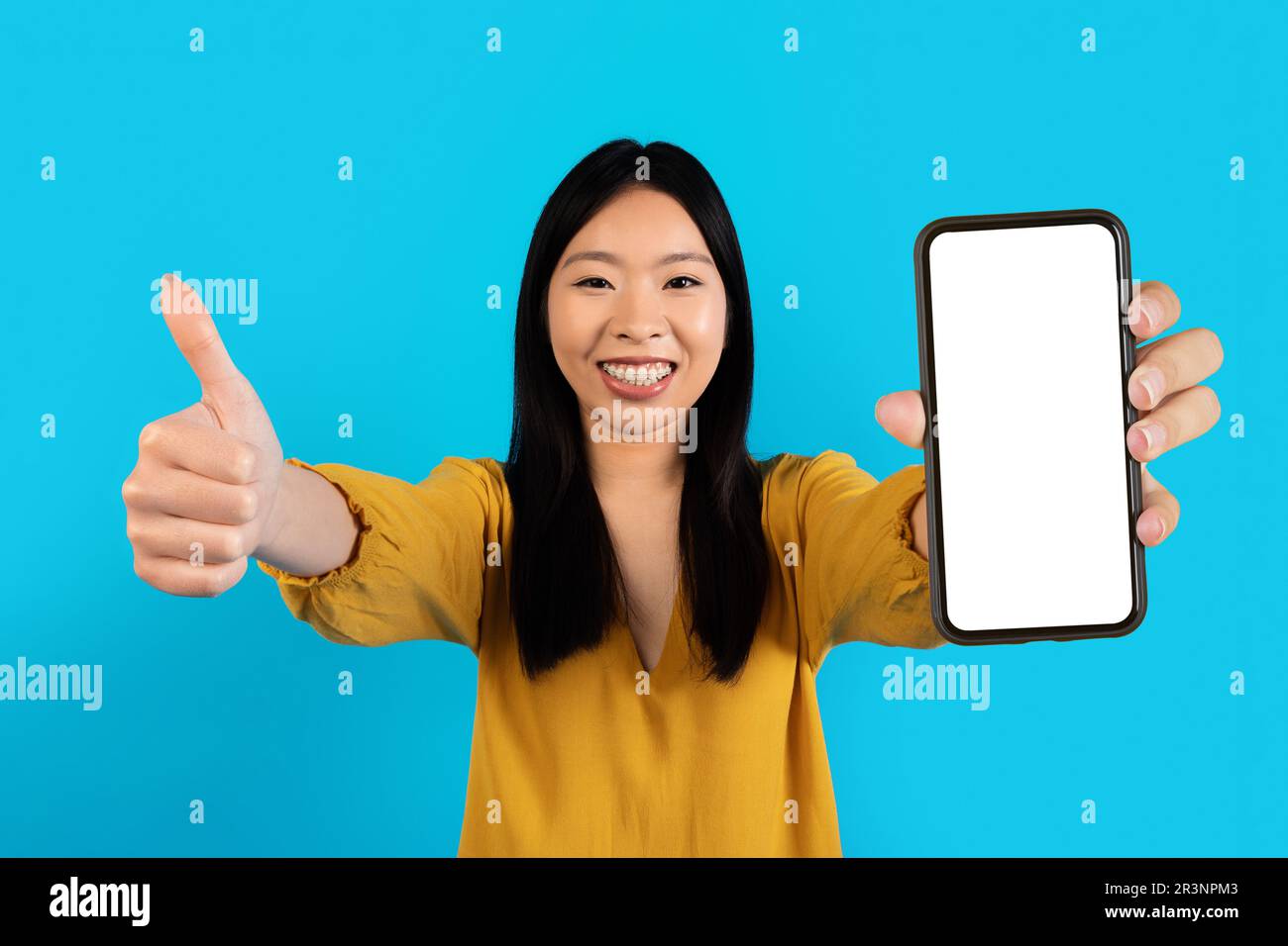 Beautiful asian woman showing smartphone with blank screen, thumb up ...