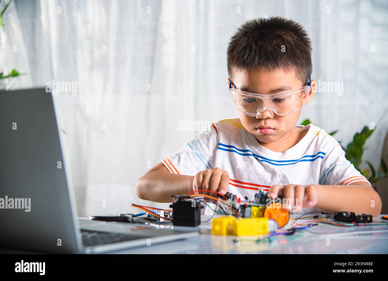 Asian kid boy assembling the Arduino robot car homework project at home ...