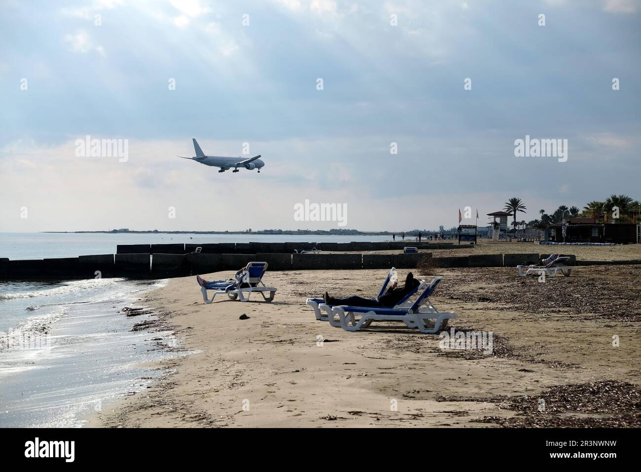 Landscape with tourists resting on deck chairs near sea and big ...