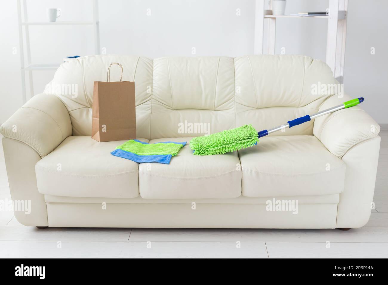 Blue and green plastic mop with adjustable handle lying on couch ...