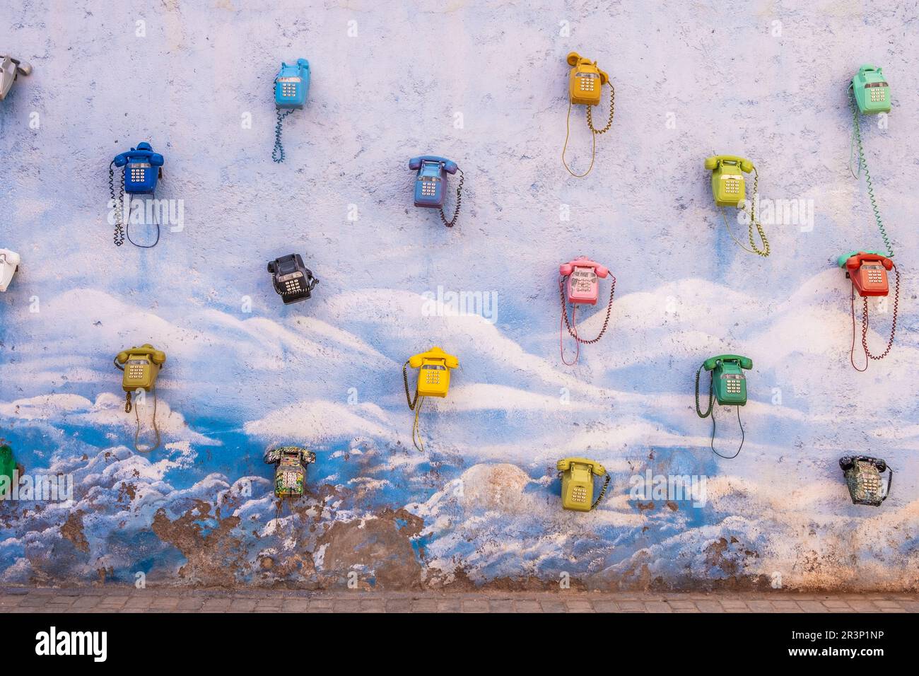 Colored telephones hanging in a blue and white wall Stock Photo - Alamy