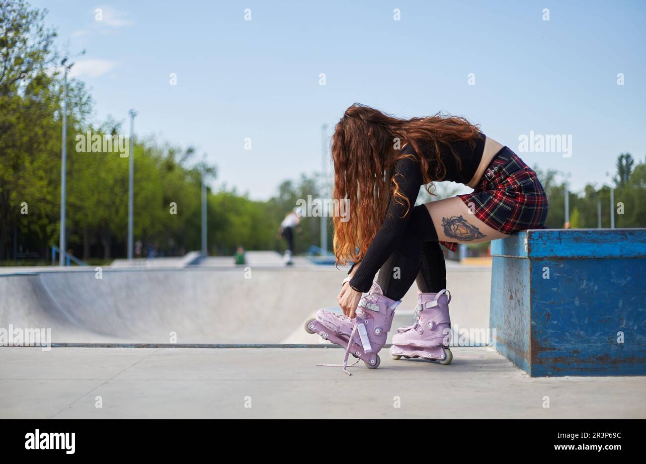 Cool young skater female putting on aggressive inline skates in a ...