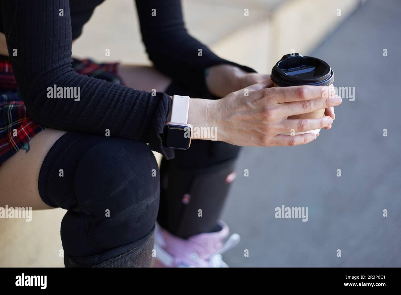 Skater girl sitting in a skatepark with a cup of coffee. Unrecognizable ...