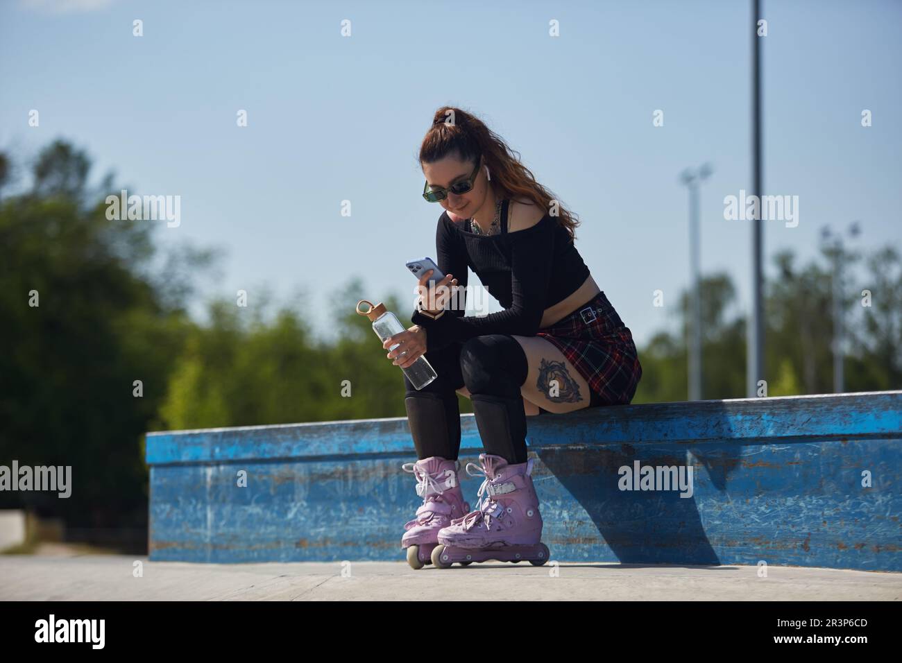 Young skater female sitting on a ledge in a skatepark with a glass ...