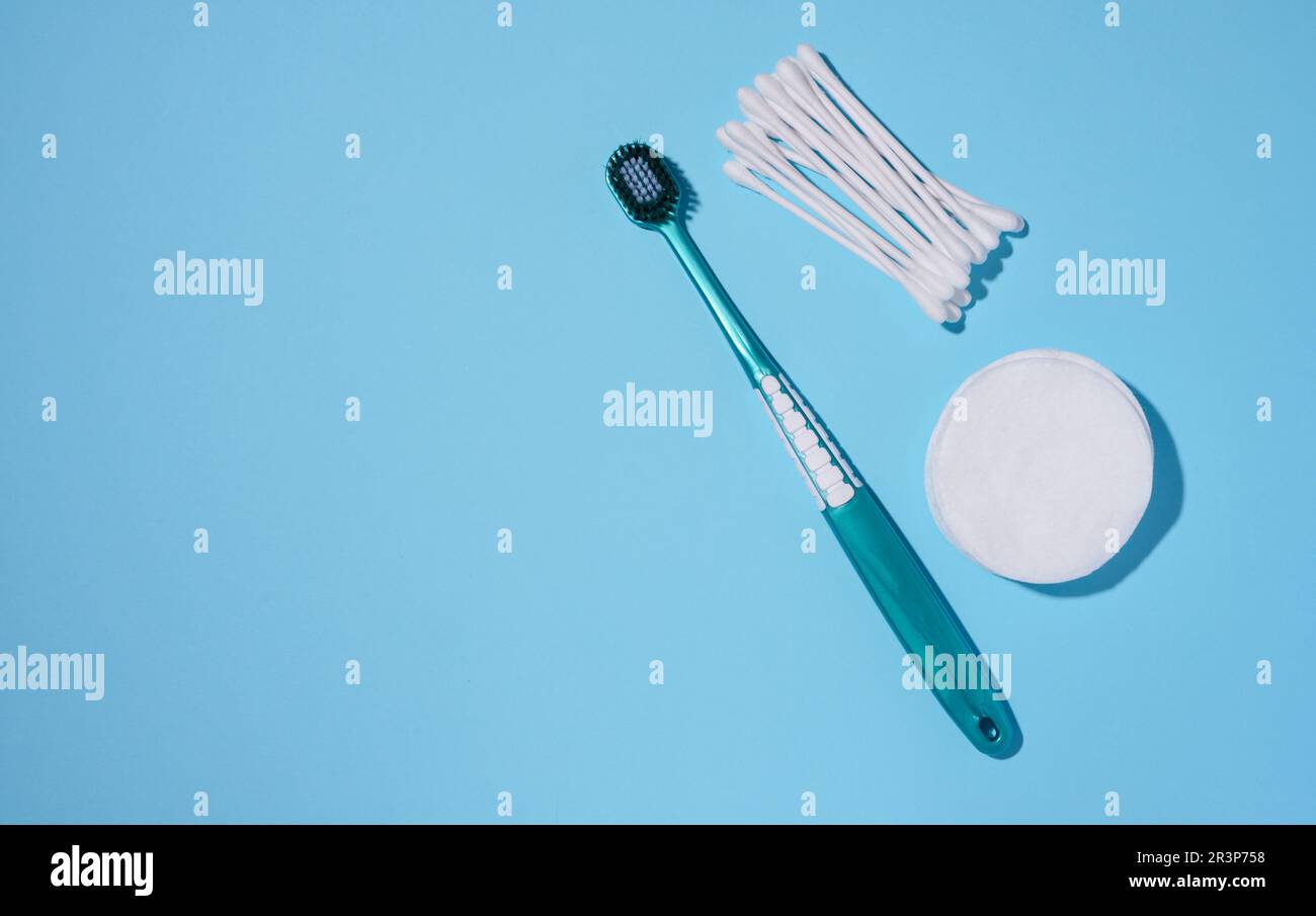 Toothbrush, round cotton sponges and cotton buds on a blue background ...